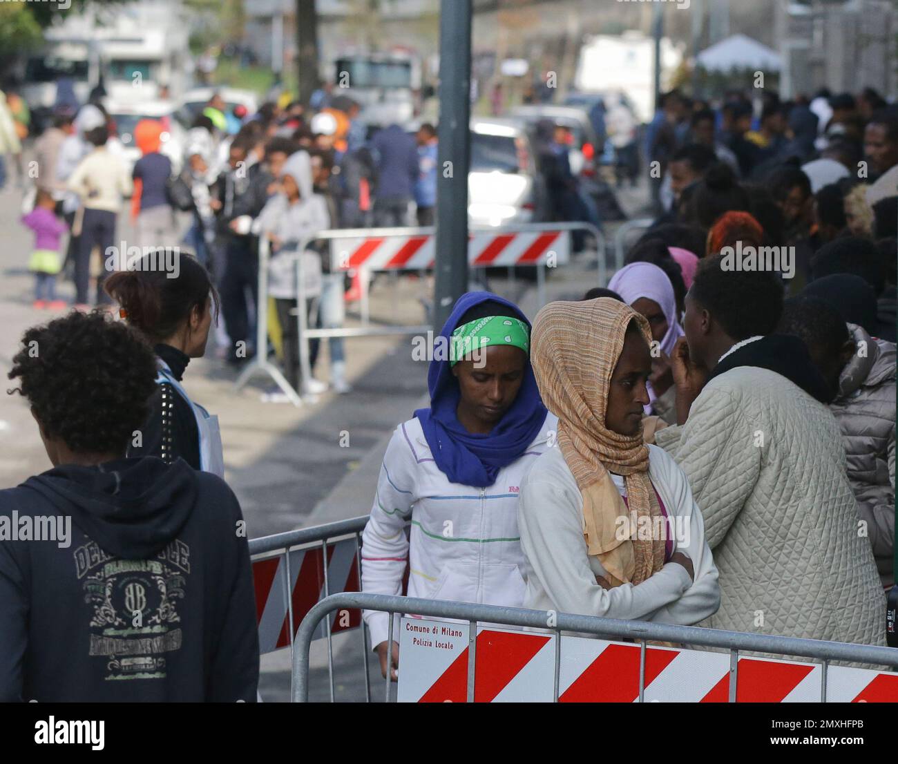 Migrants queue waiting to enter the refectory at a refugee hub in Milan ...