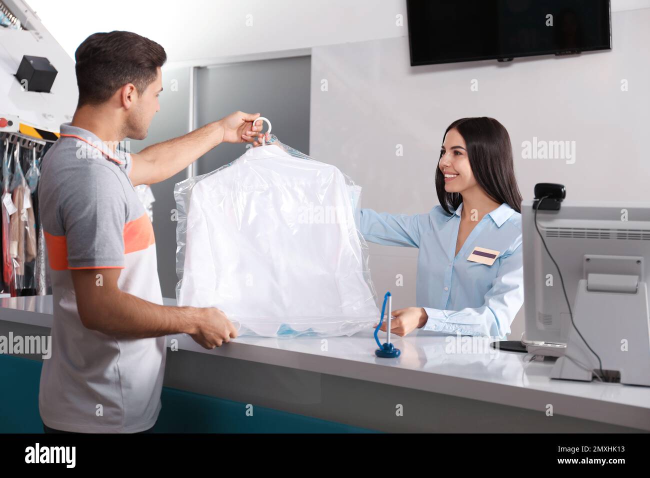 Female worker giving shirt to client at dry-cleaner's Stock Photo - Alamy