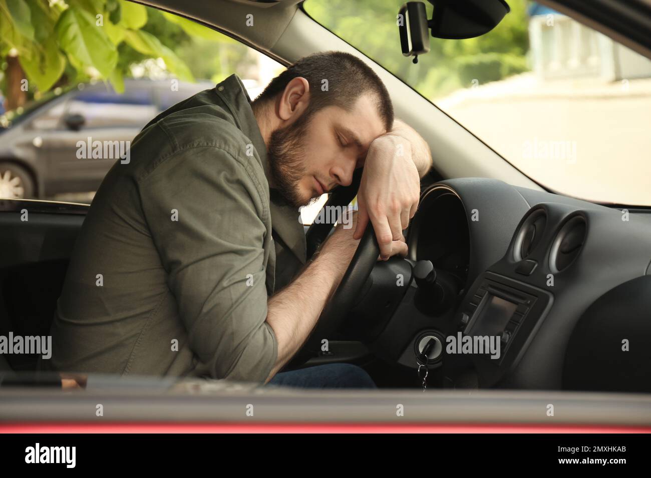 Tired man sleeping on steering wheel in his car Stock Photo - Alamy
