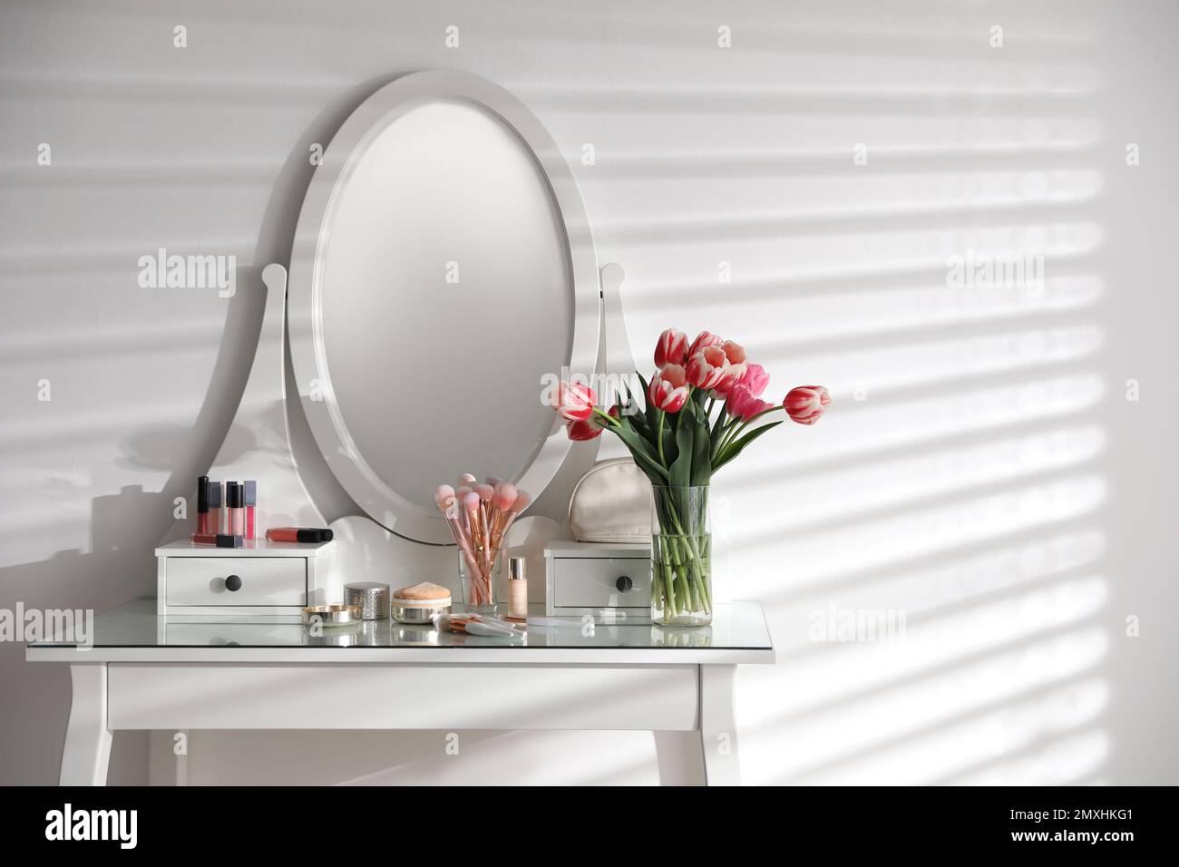 Elegant dressing table with makeup products, accessories and tulips indoors. Interior element ...