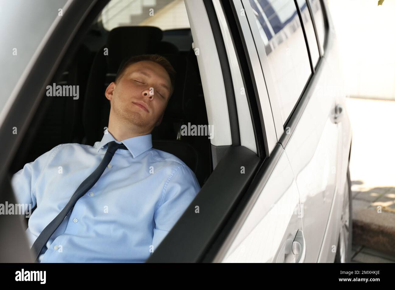 Tired young man sleeping in his modern car Stock Photo - Alamy