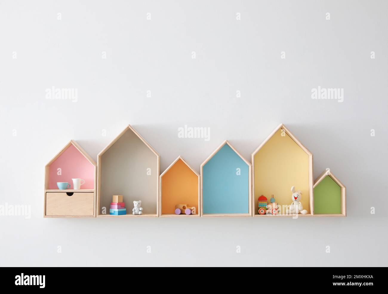 Different house shaped shelves with toys on white wall. Interior design ...