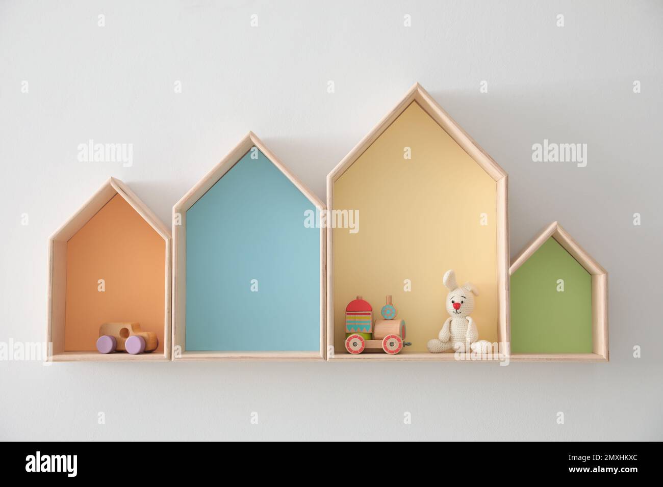 Different house shaped shelves with toys on white wall. Interior design ...