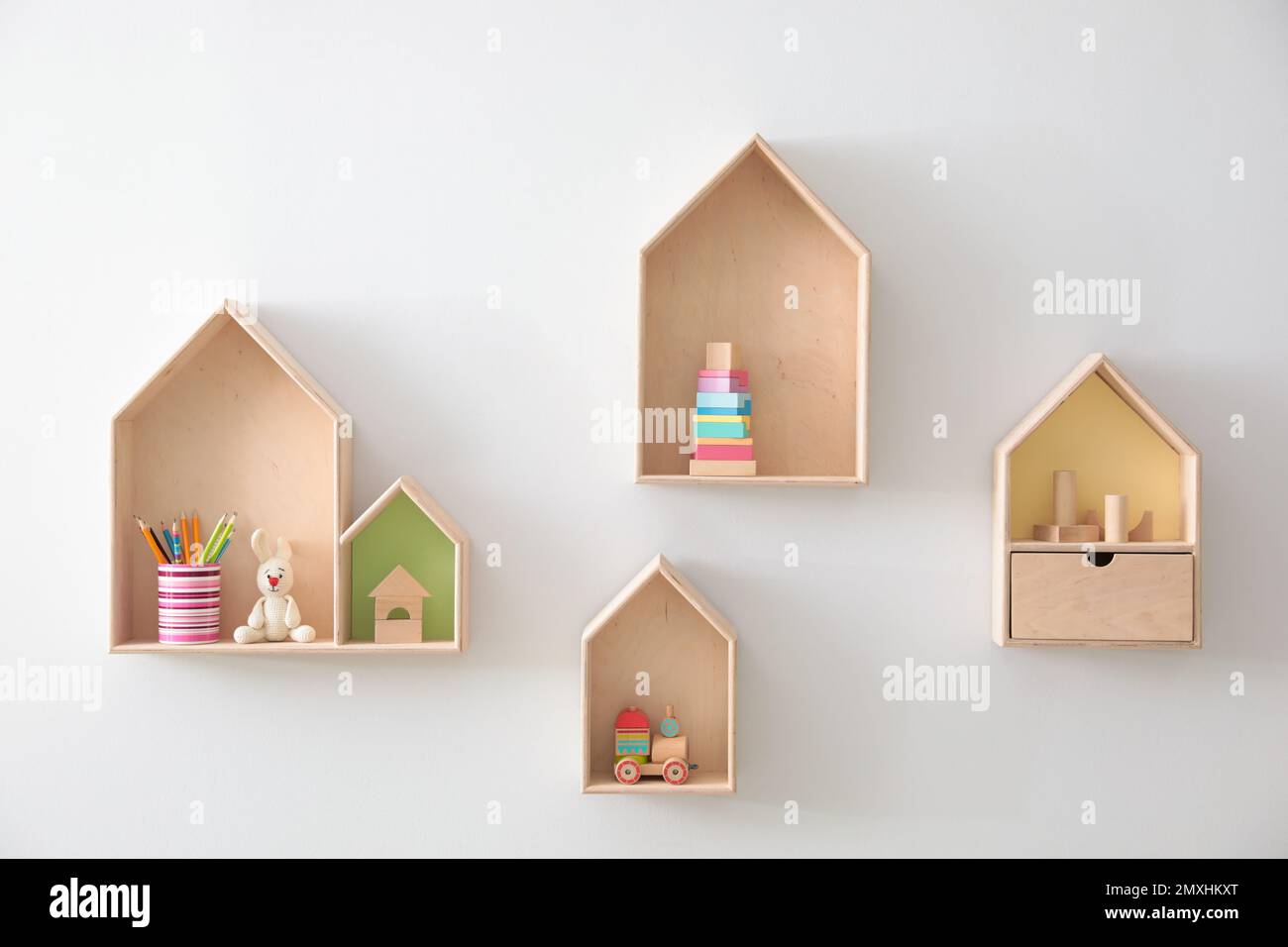 Different house shaped shelves with toys on white wall. Interior design ...