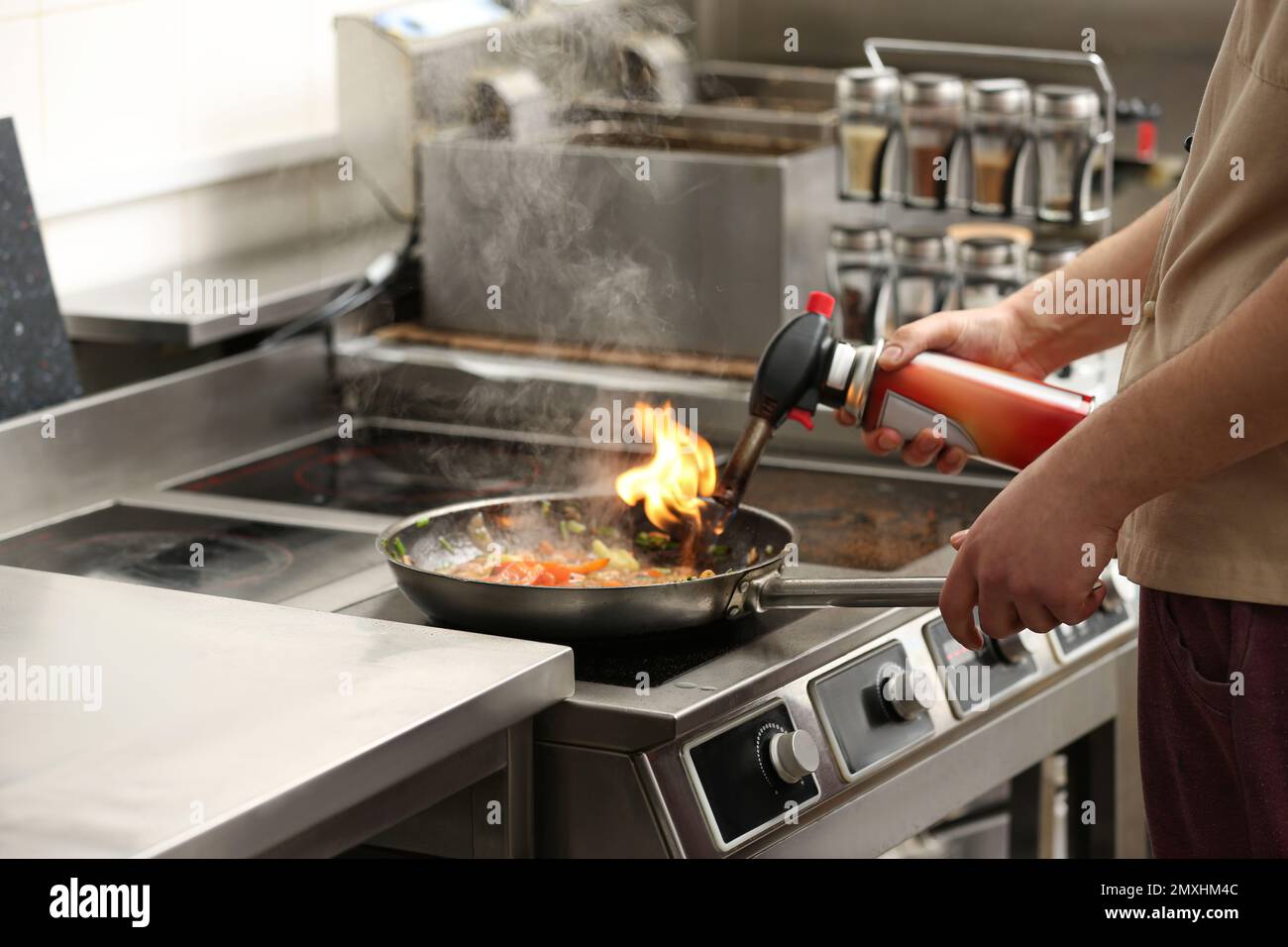 Male chef with manual gas burner cooking tasty food on stove in ...