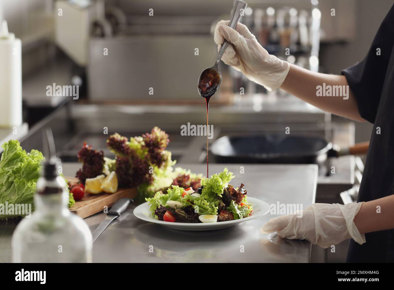 Female chef adding sauce to cooking food in restaurant kitchen, closeup ...
