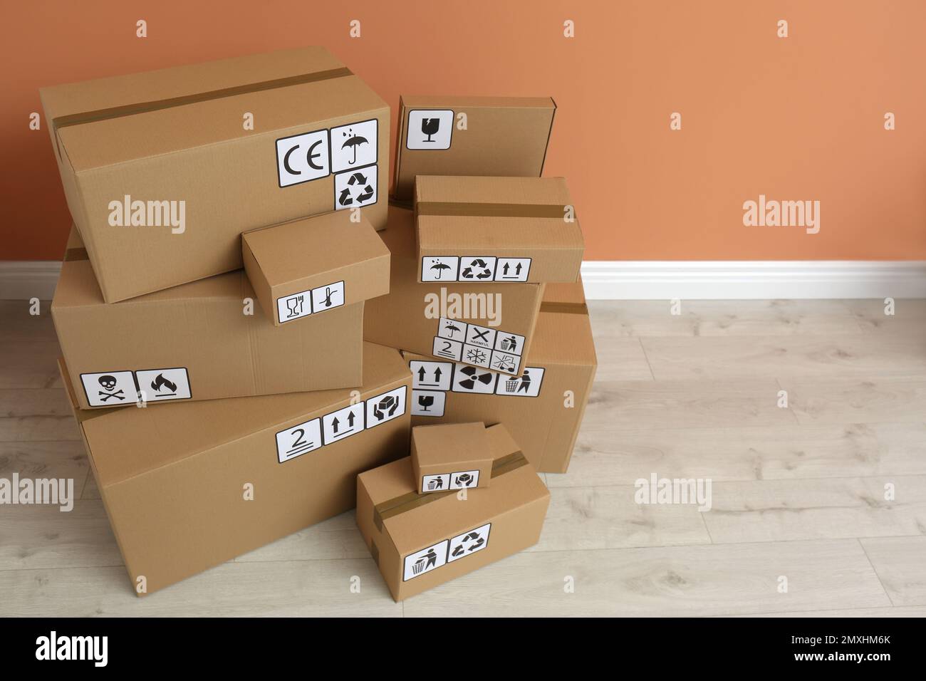 Cardboard boxes with different packaging symbols on floor near orange ...