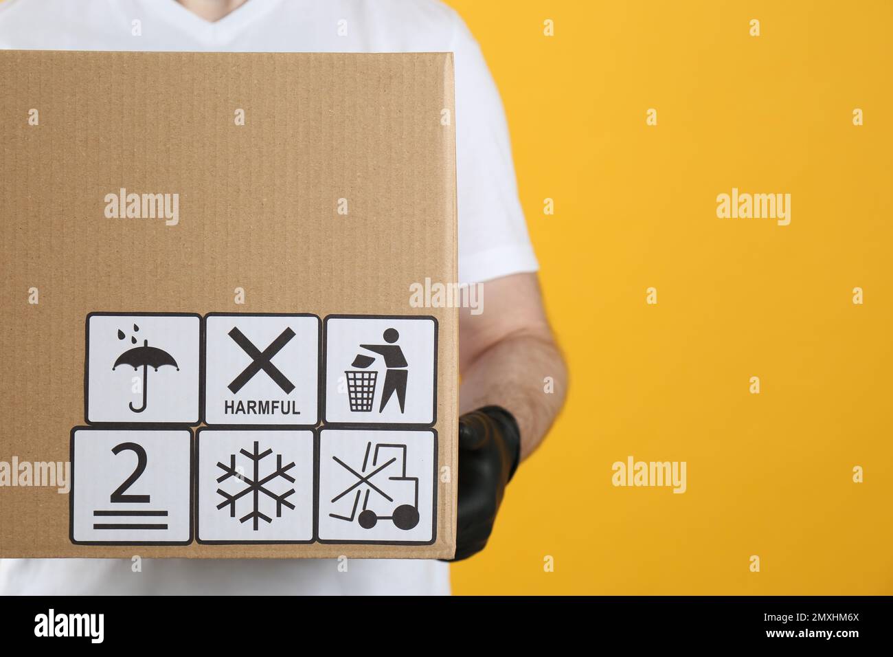 Courier holding cardboard box with different packaging symbols on ...