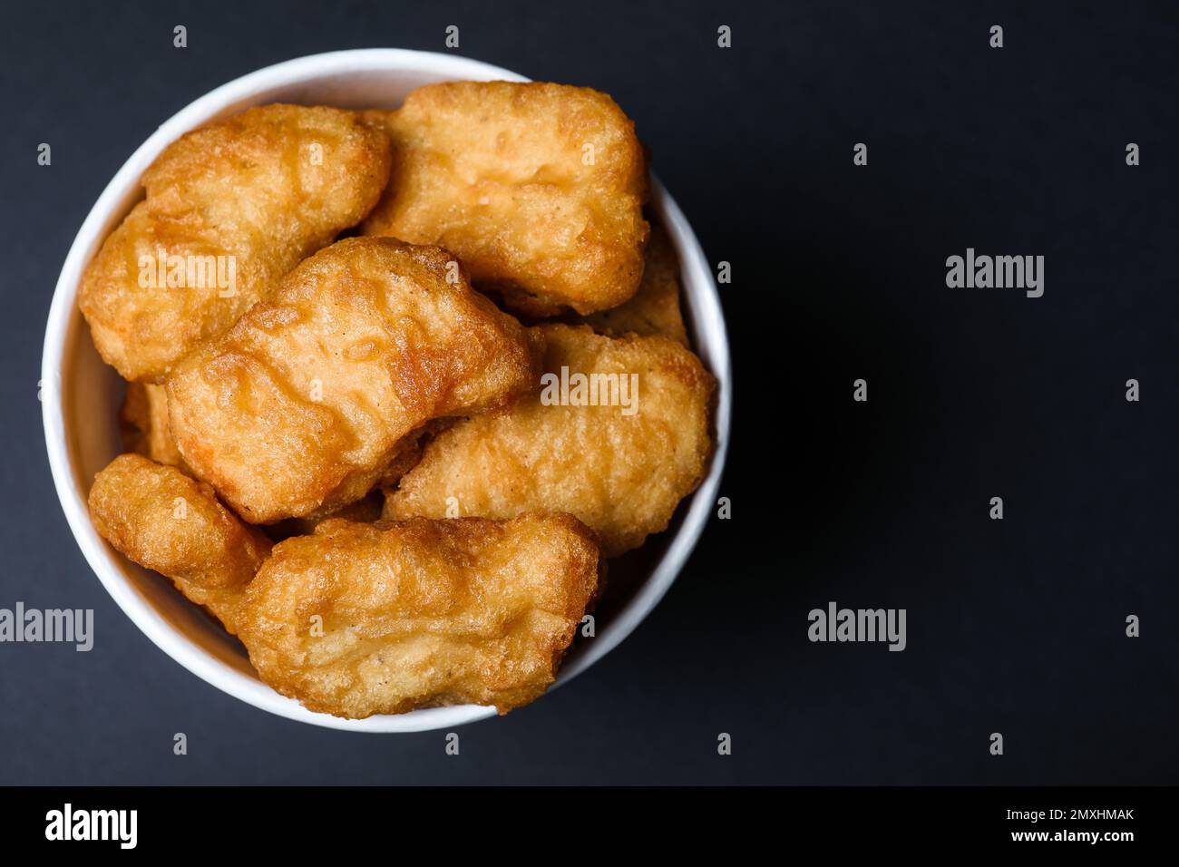 Bucket with delicious chicken nuggets on black background, top view ...