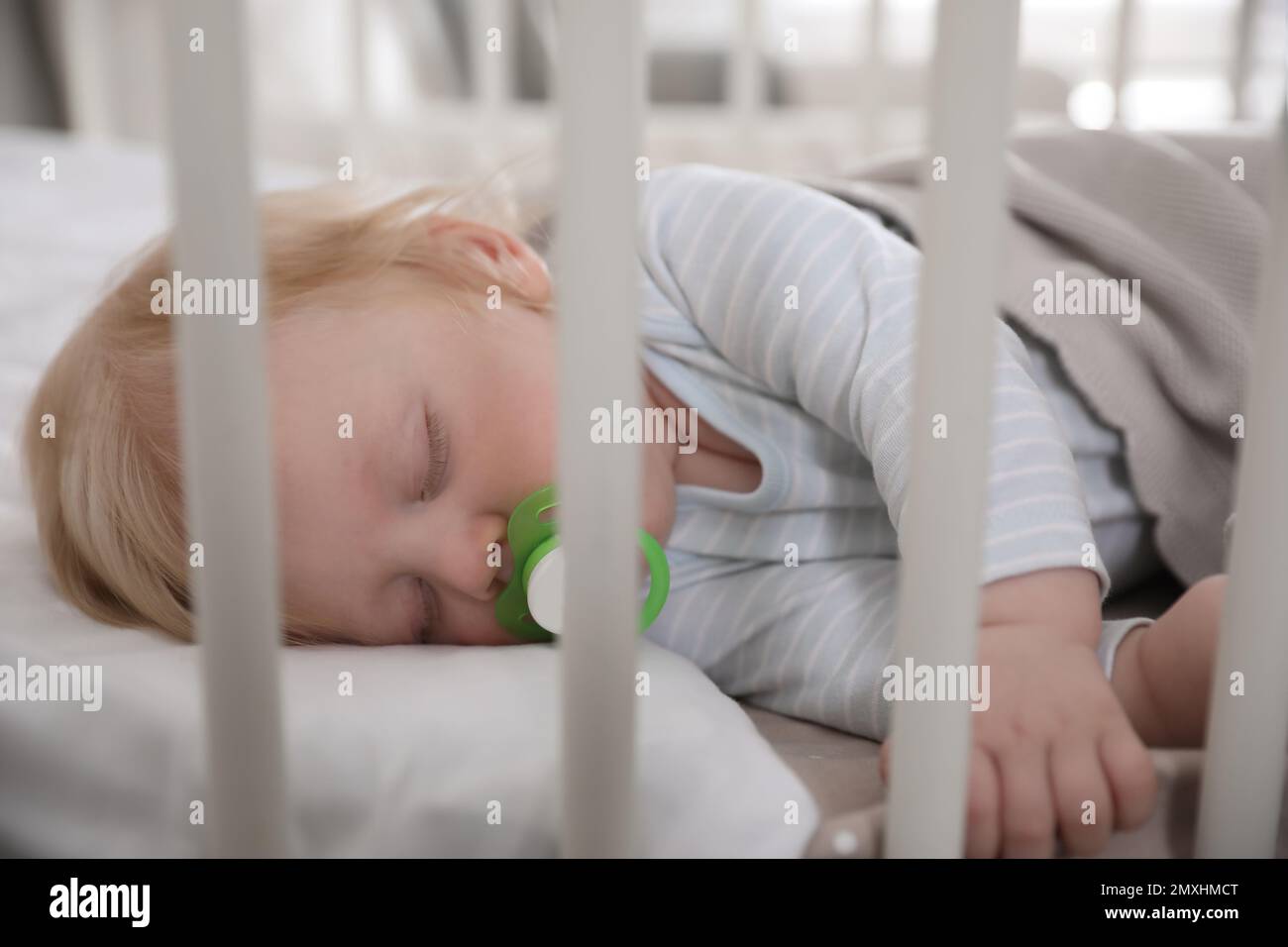 Cute little baby with pacifier sleeping in crib. Bedtime Stock Photo ...