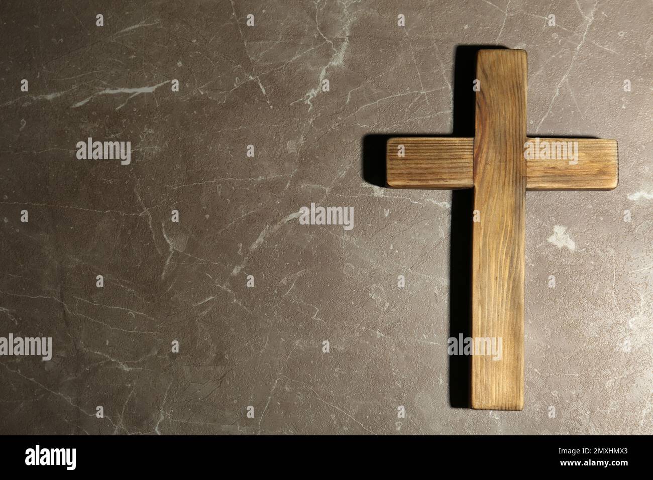 Wooden Christian cross on brown marble table, top view with space for ...