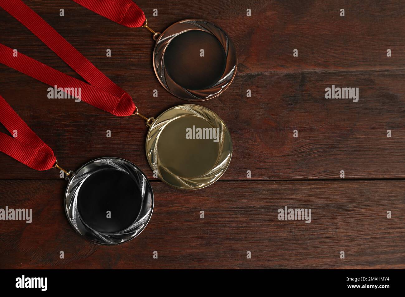 Gold, silver and bronze medals on wooden background, flat lay. Space ...