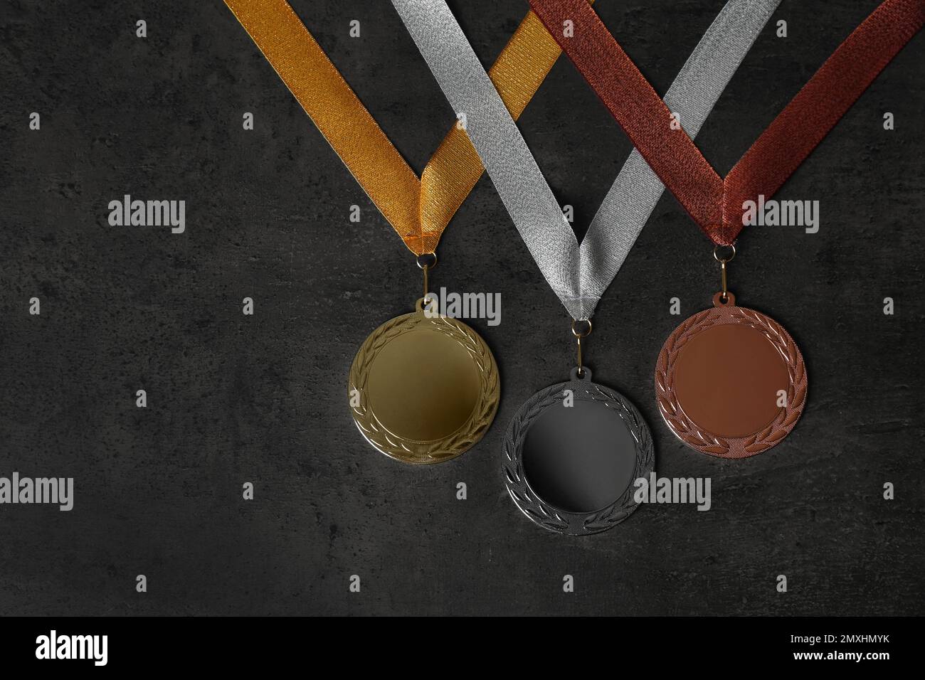 Gold, silver and bronze medals on grey stone background, flat lay ...
