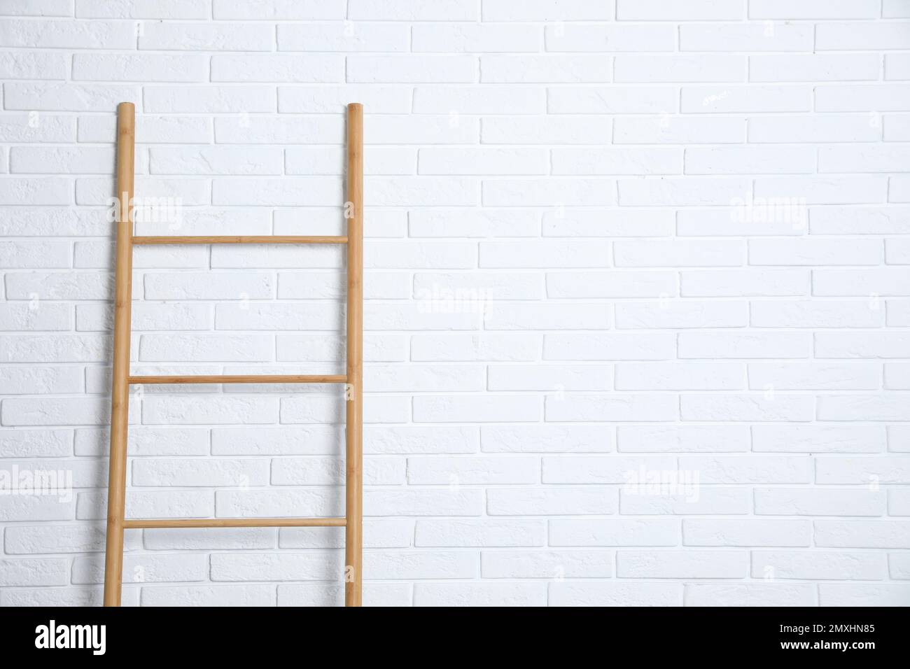 Modern wooden ladder near white brick wall. Space for text Stock Photo ...