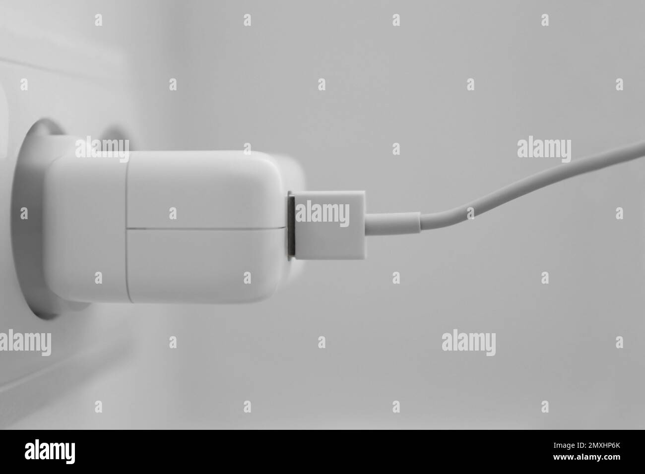 Charging adapter plugged in electric socket, closeup Stock Photo - Alamy