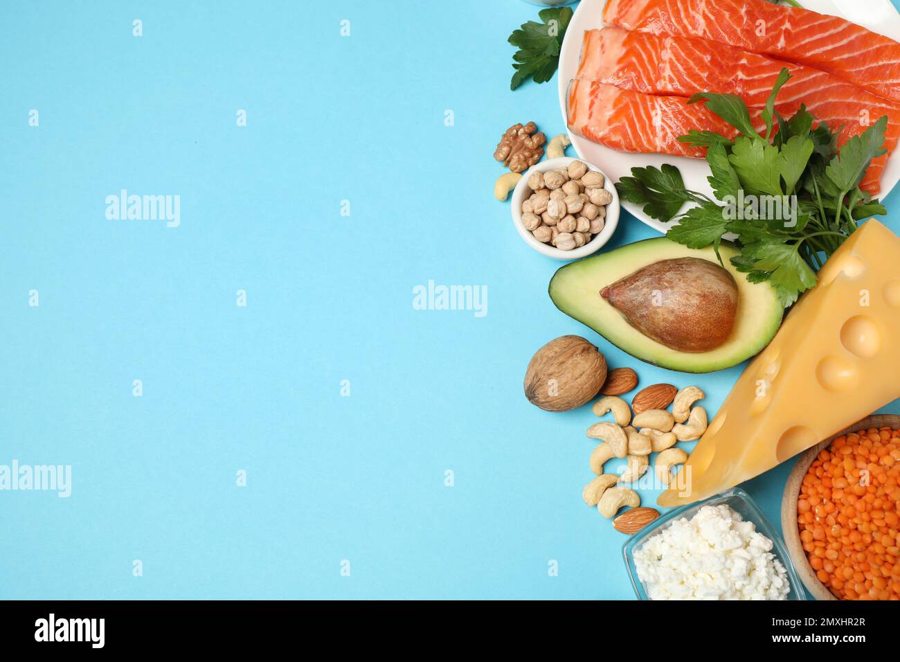 Different products rich in protein on light blue background, flat lay ...