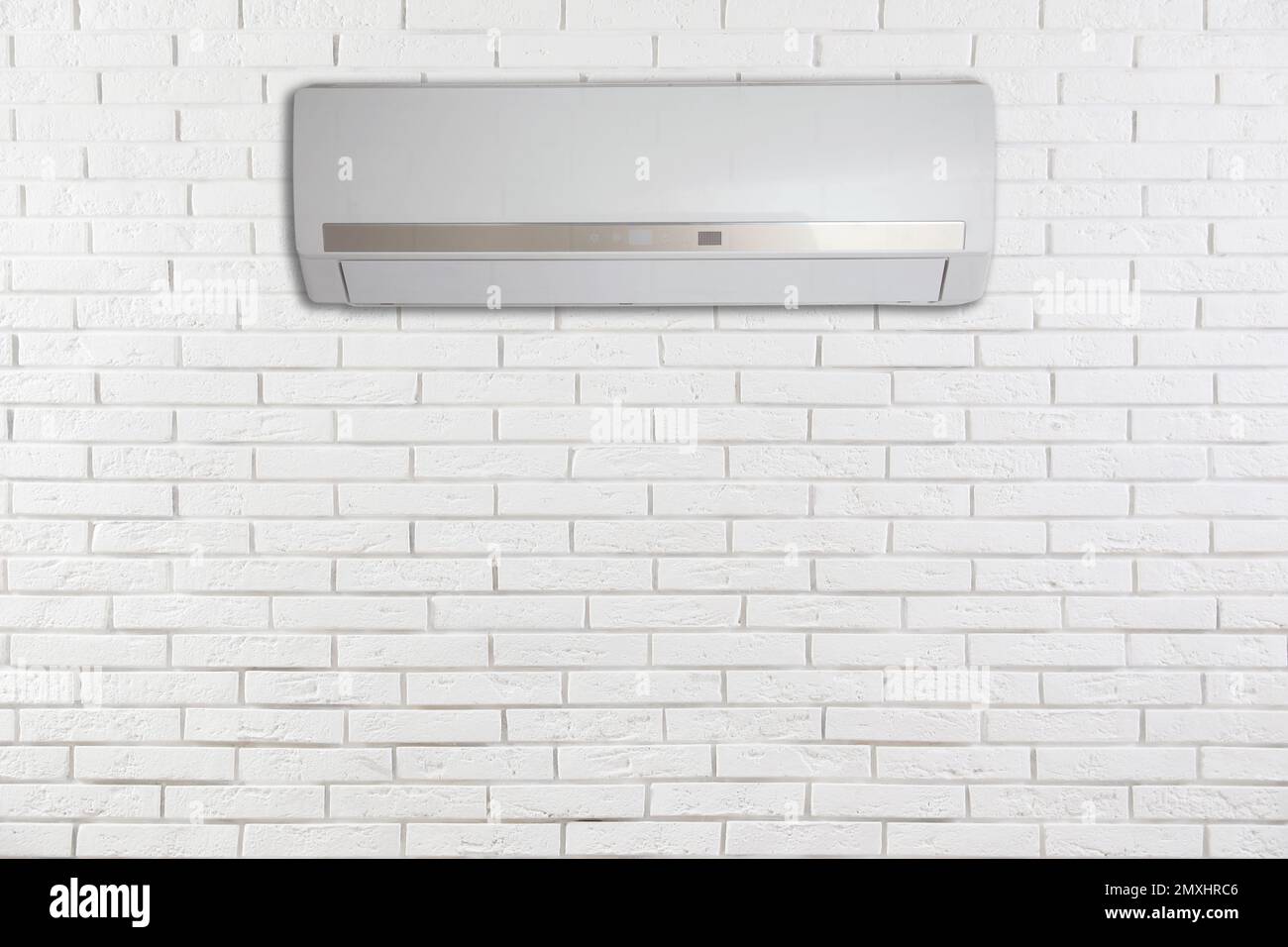 Modern air conditioner on white brick wall indoors Stock Photo - Alamy