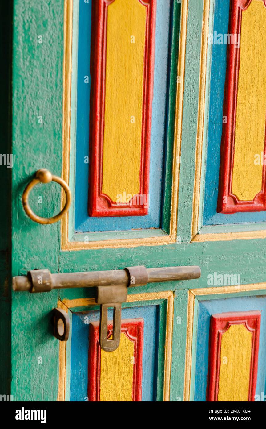 A closeup of a colorful wooden door with a knocker and a wooden door ...