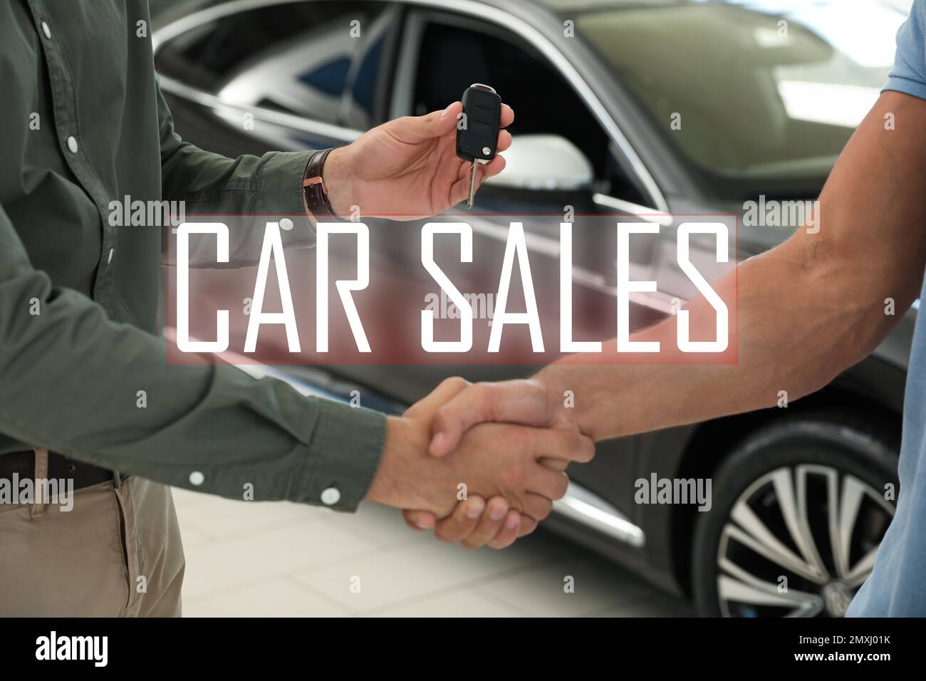 Young salesman shaking hands with customer and giving car key in modern ...