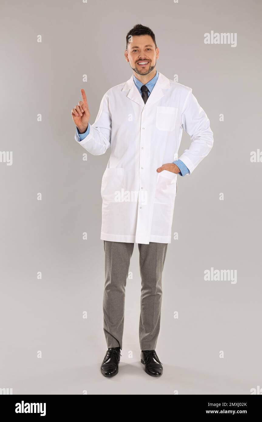 Happy man in lab coat on light grey background Stock Photo - Alamy