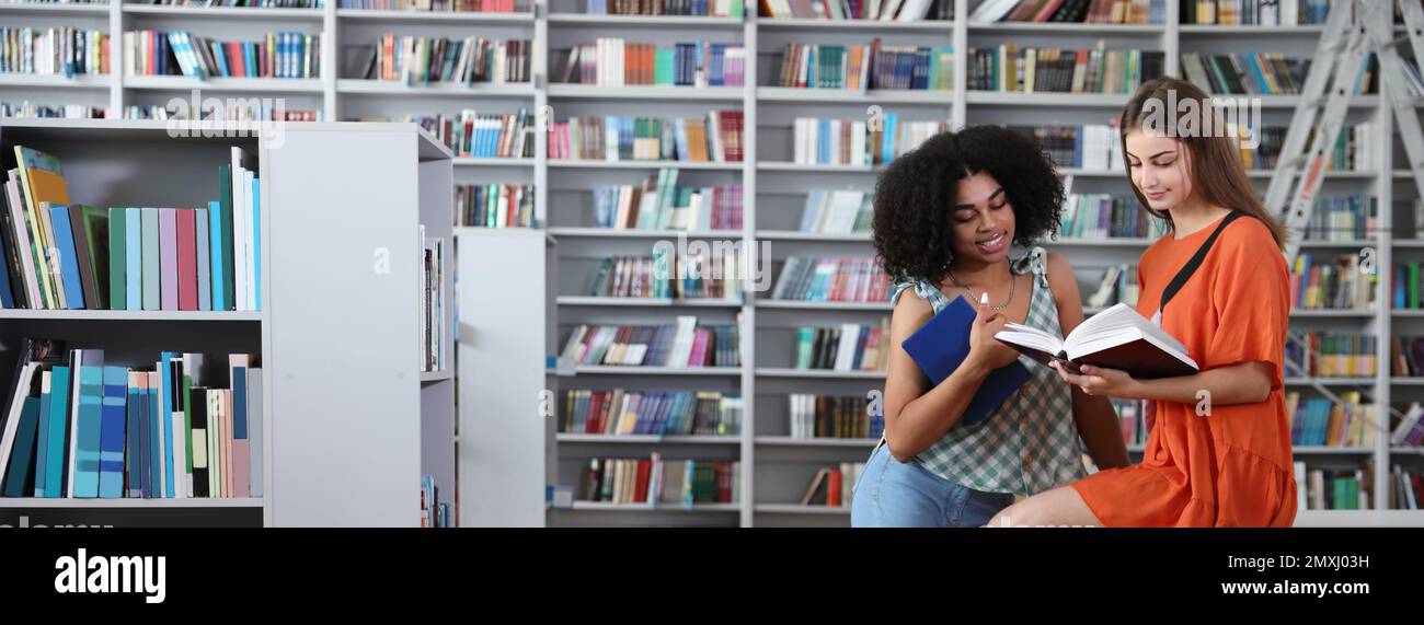 Young students with books in modern library, space for text. Banner ...