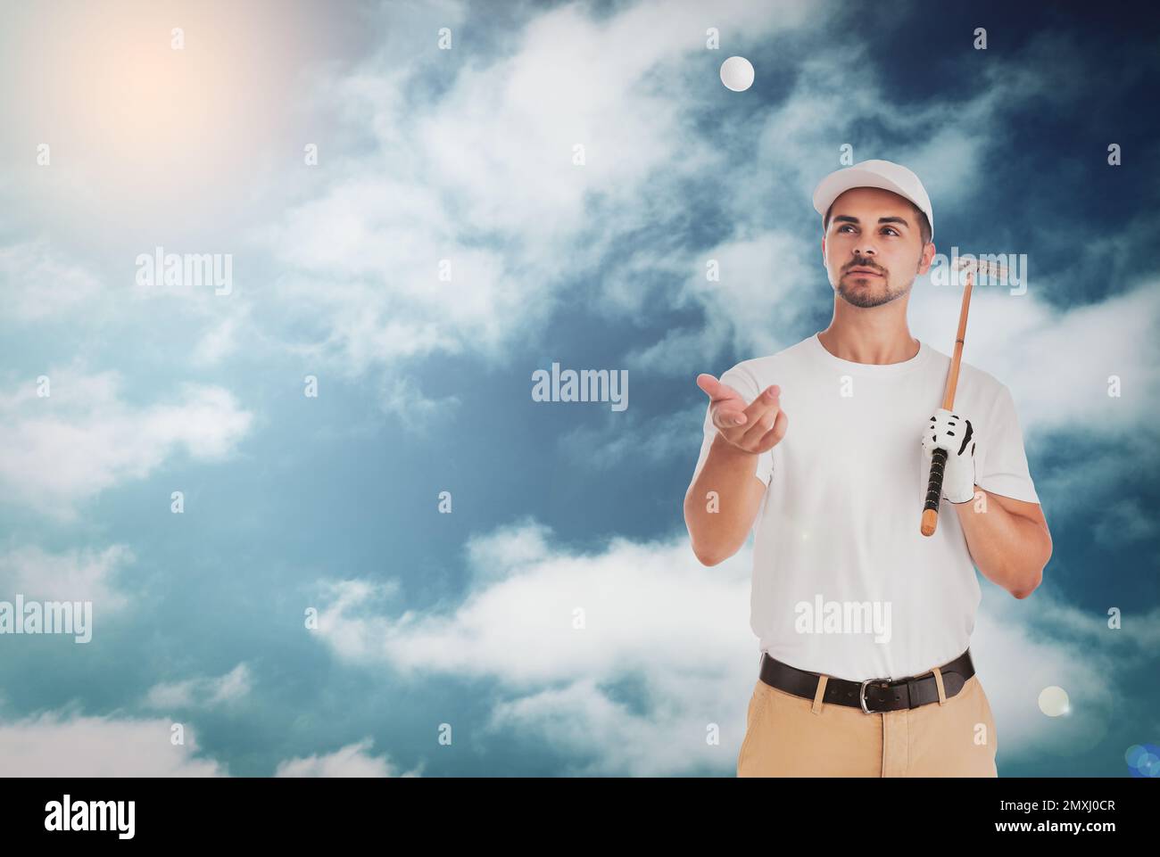 Young man with golf club and ball against blue sky. Space for design ...