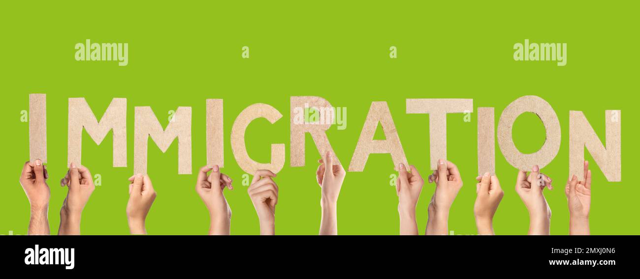 People holding word IMMIGRATION made of cardboard letters on green ...