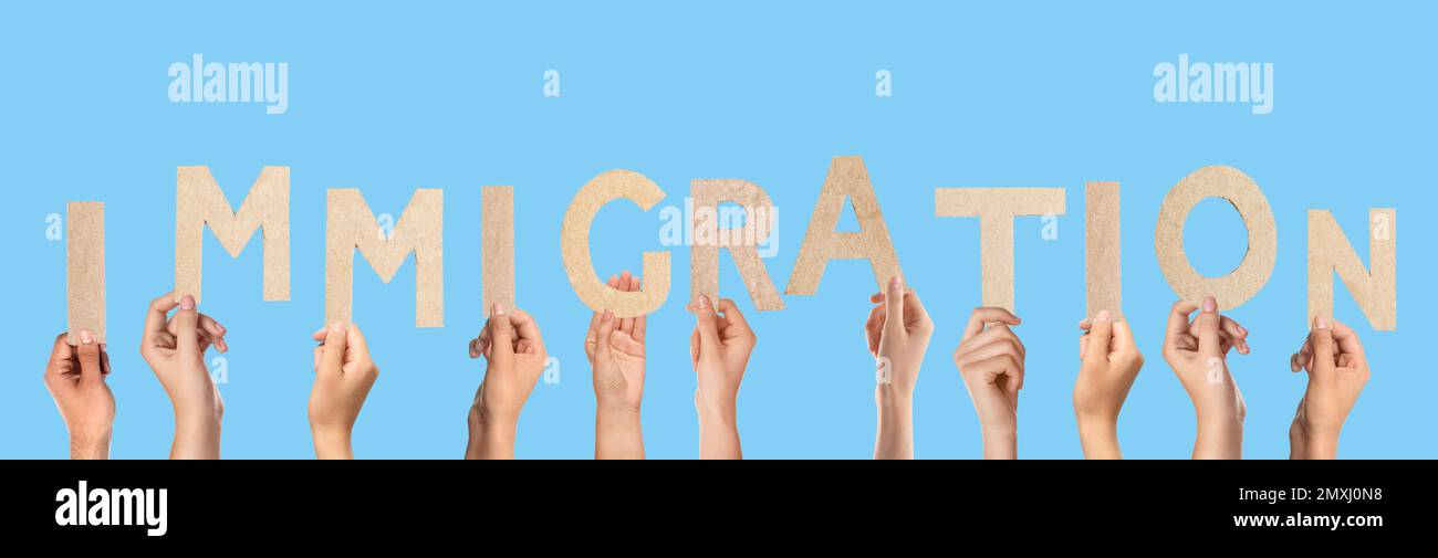 People holding word IMMIGRATION made of cardboard letters on light blue ...
