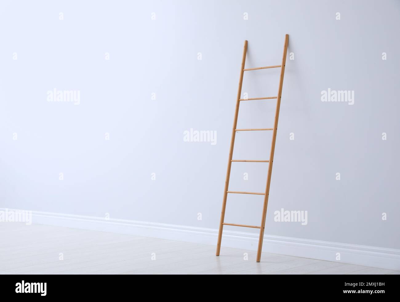 Modern wooden ladder near white wall. Space for text Stock Photo - Alamy