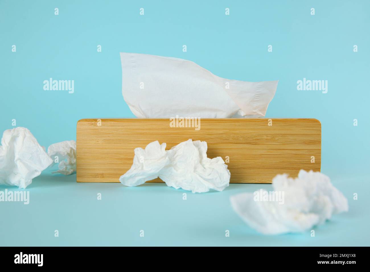 Used paper tissues and wooden holder on light blue background Stock ...