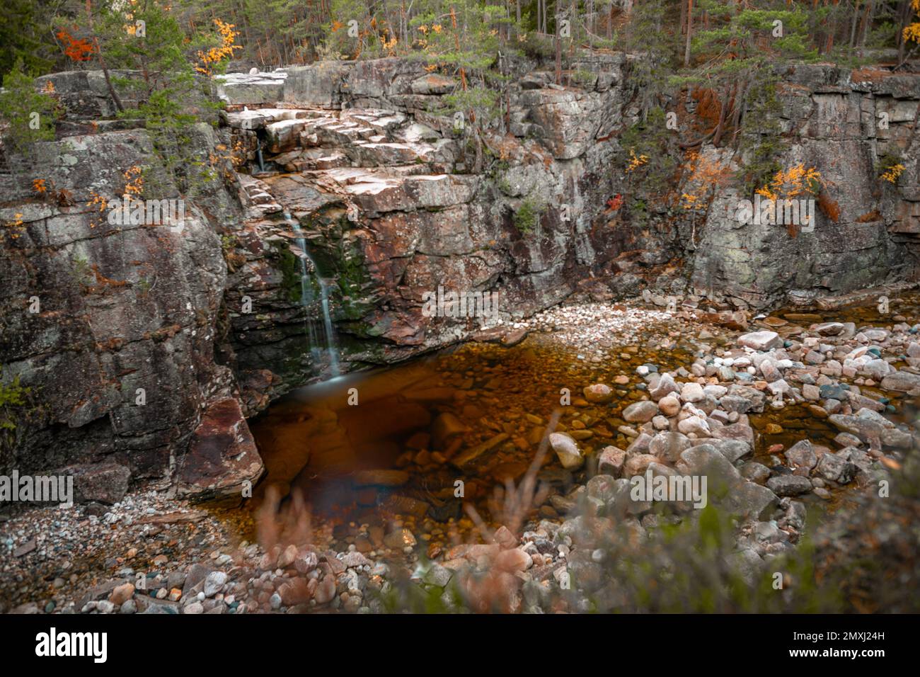 A waterfall flowing over the rock formation surrounded by stones in the ...