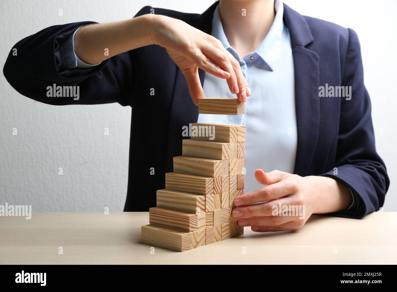 Woman building steps with wooden blocks at table, closeup. Career ...