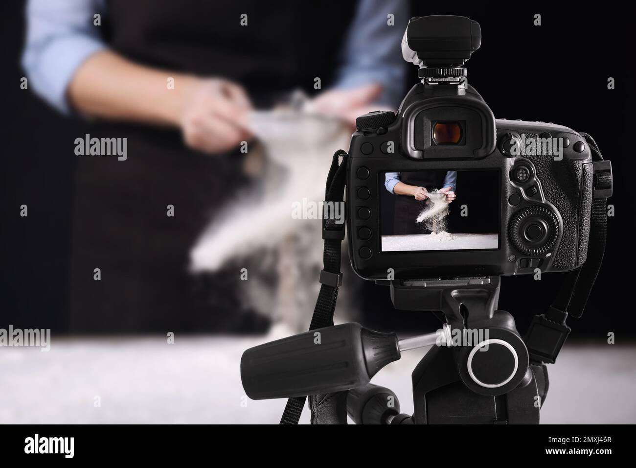 Food photography. Shooting of woman sifting flour, focus on camera ...