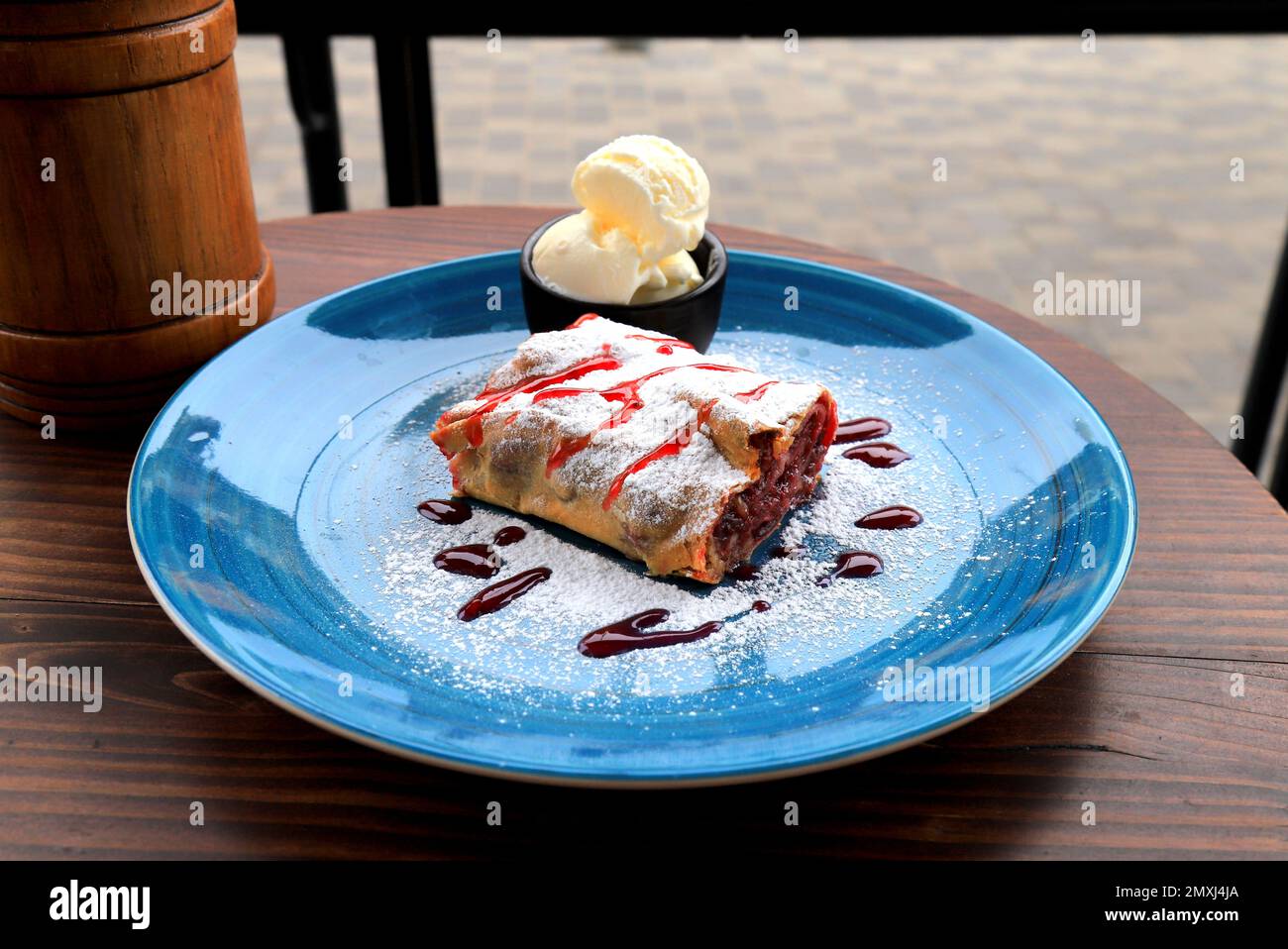 Viennese fruit strudel and ice cream on blue plate in cafe, restaurant ...
