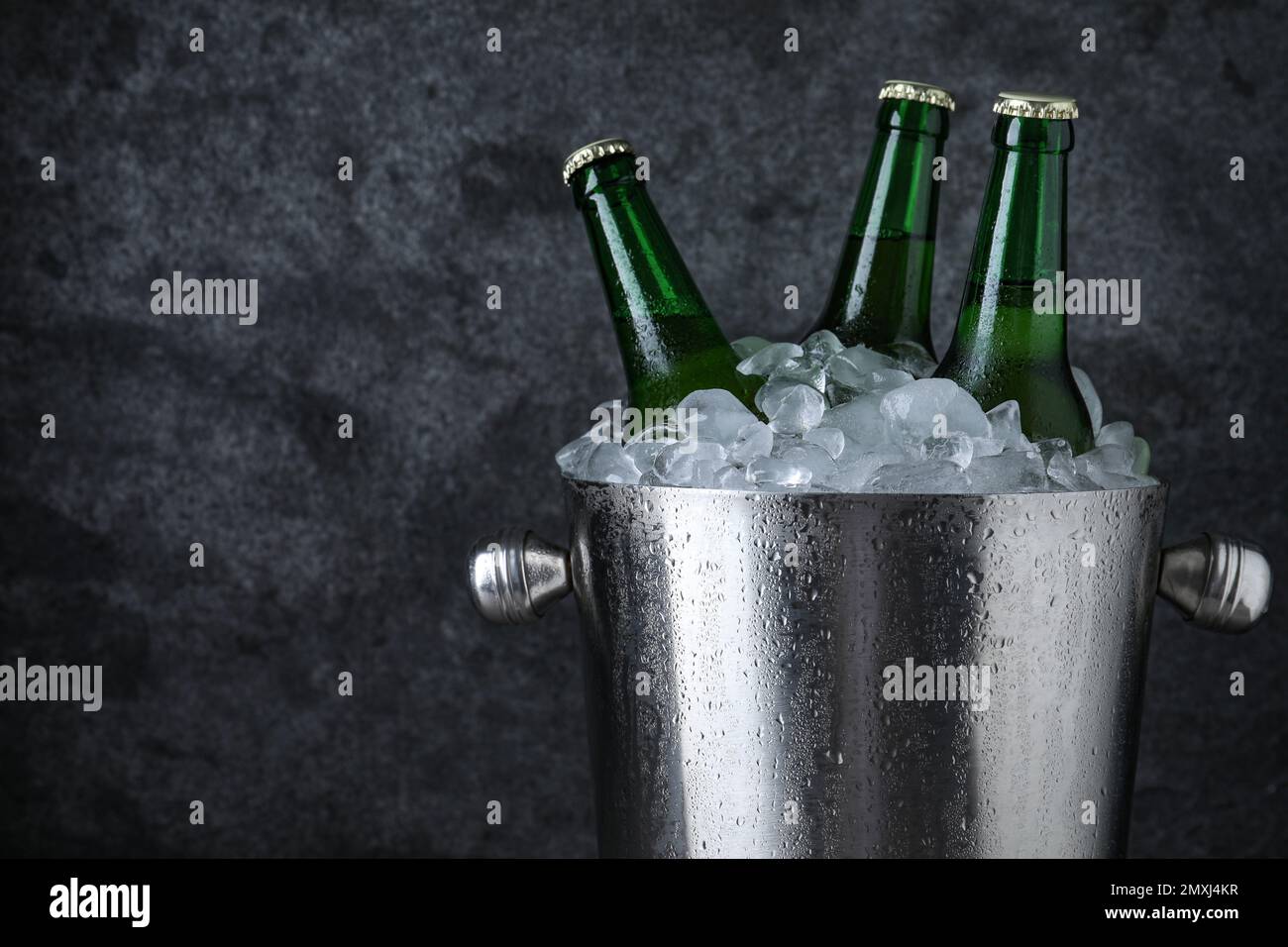 Metal bucket with beer and ice cubes on grey background, closeup. Space ...