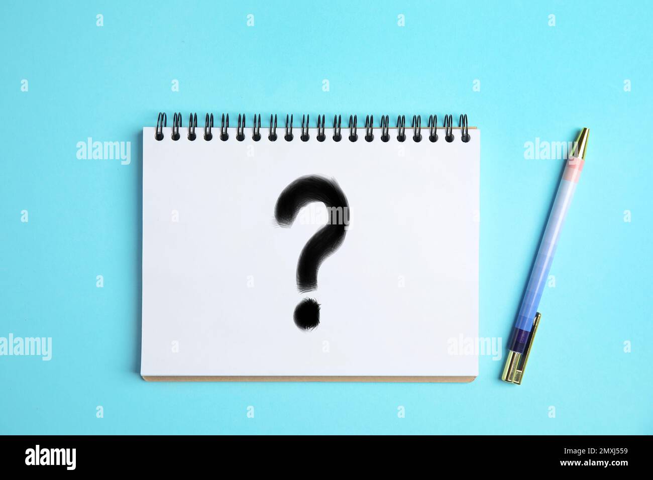 Notebook with question mark and pen on light blue background, top view ...