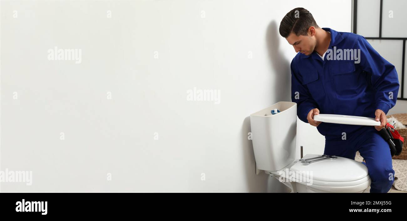 Professional plumber working with toilet bowl in bathroom, space for ...