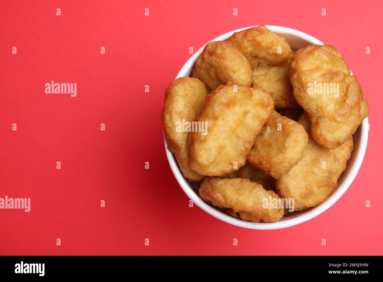 Bucket with delicious chicken nuggets on red background, top view ...