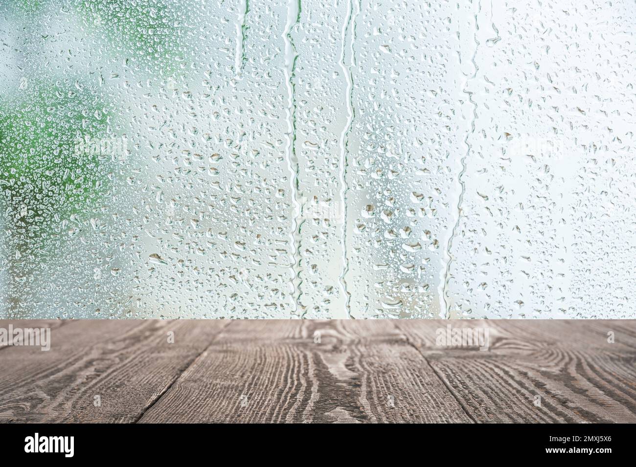 Wooden table near window on rainy day Stock Photo - Alamy