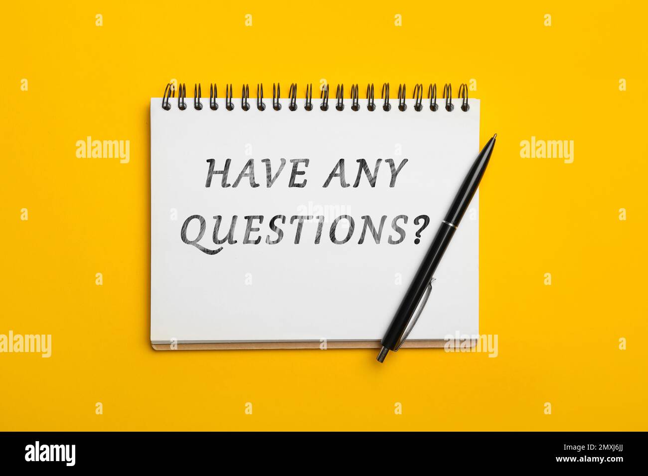 Open notebook with phrase HAVE ANY QUESTIONS and pen on yellow ...