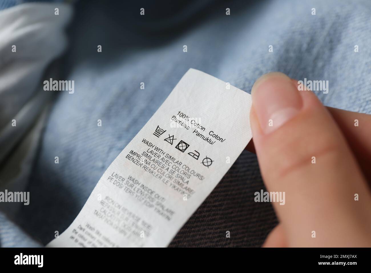 Woman reading clothing label with care symbols and material content on ...
