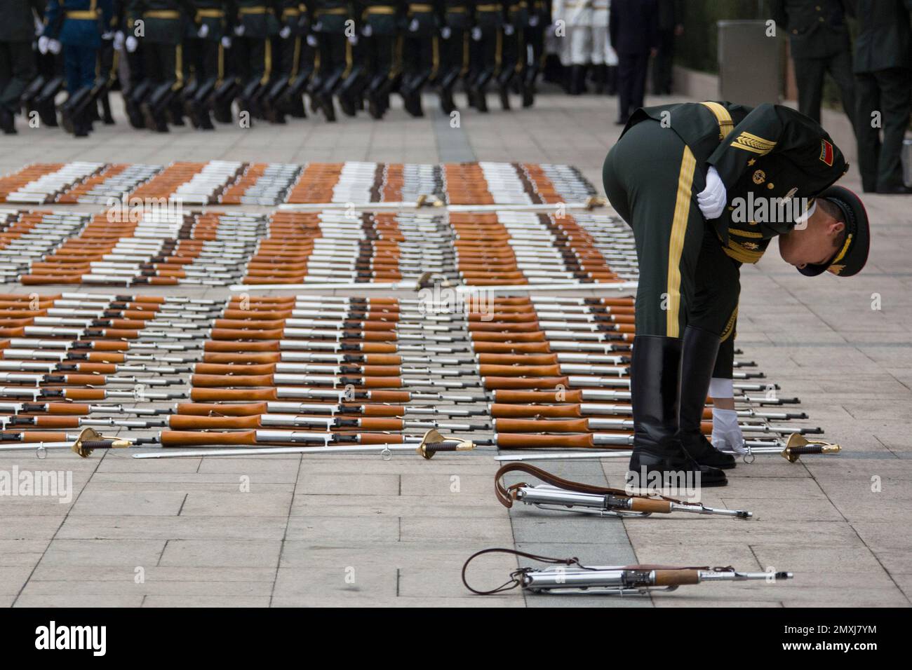 A member of a Chinese honor guard adjusts ceremonial rifles placed on ...