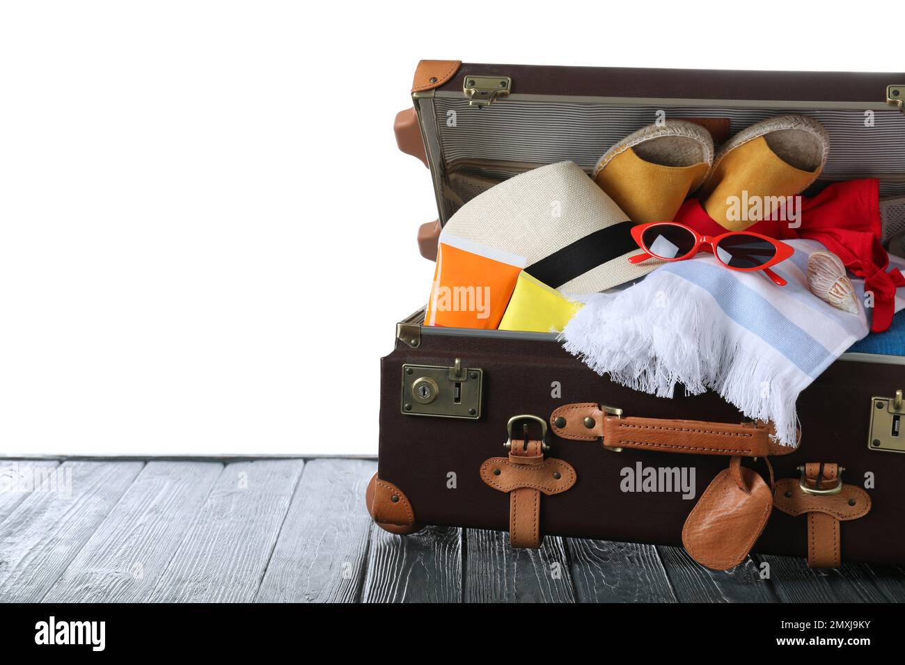 Open vintage suitcase with different beach objects on grey wooden table ...