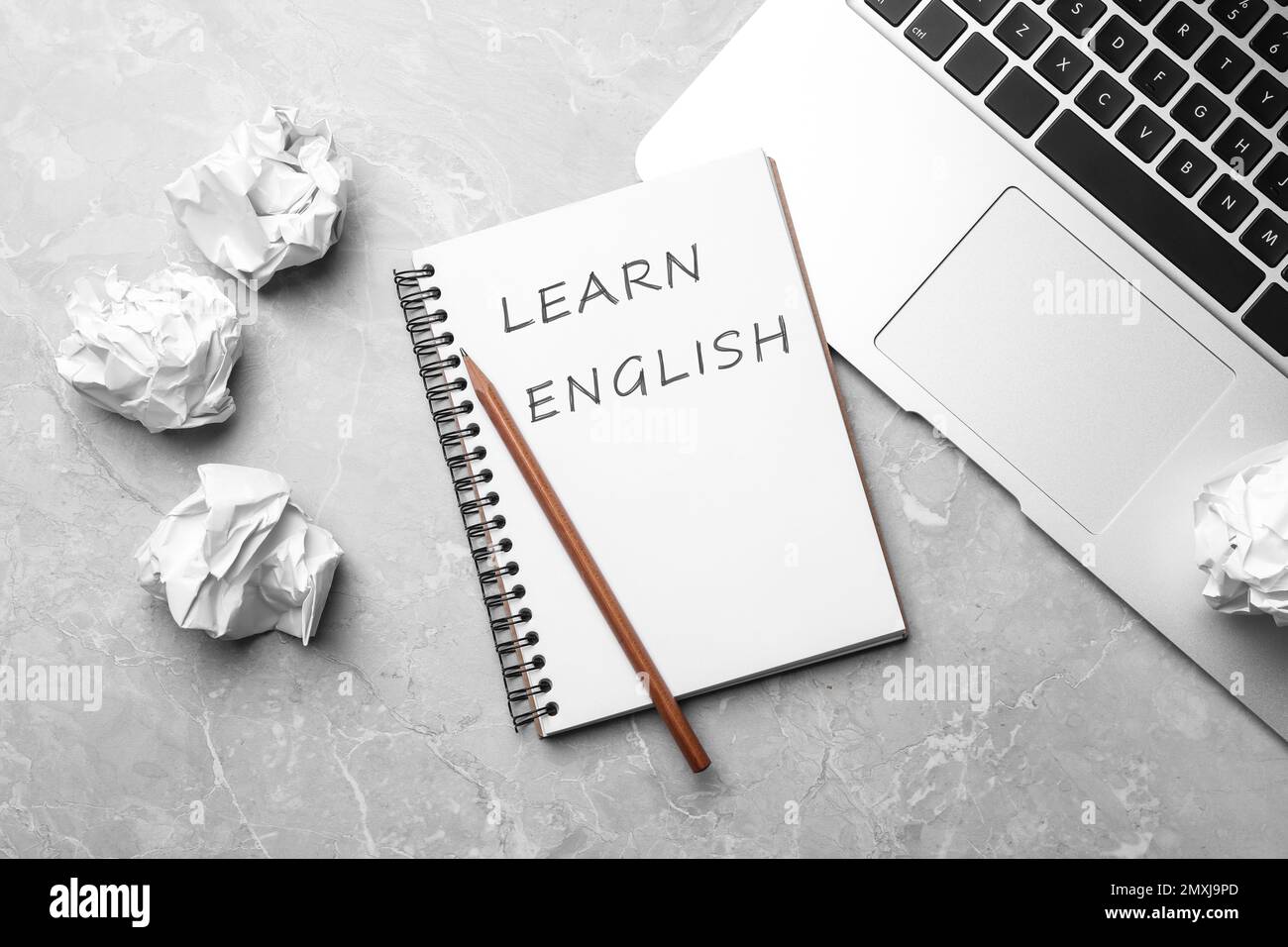 Notebook with text Learn English, laptop and crumpled paper on grey ...