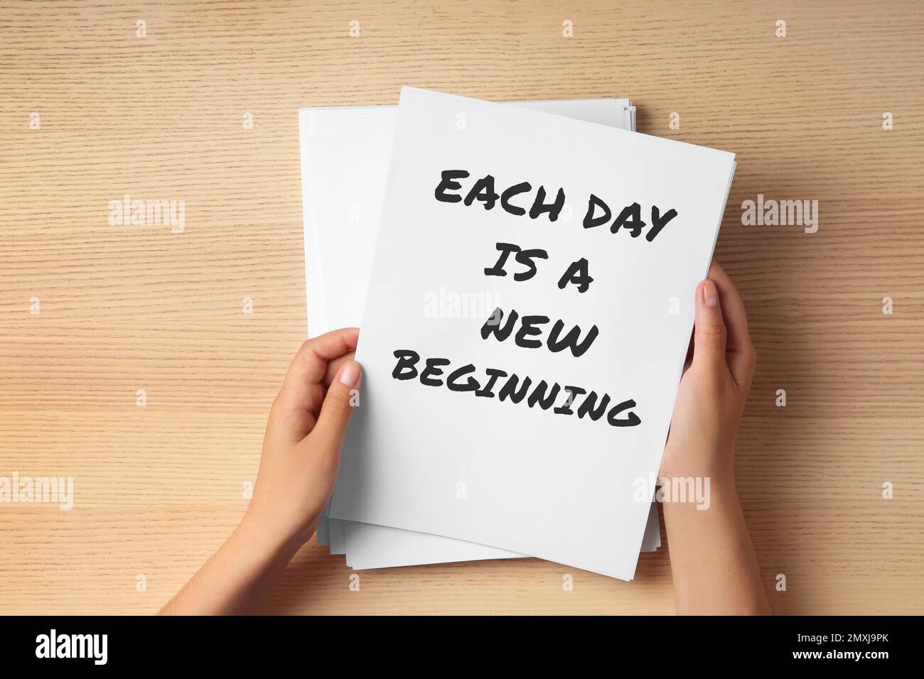 Woman holding paper with inspirational text Each Day Is A New Beginning ...