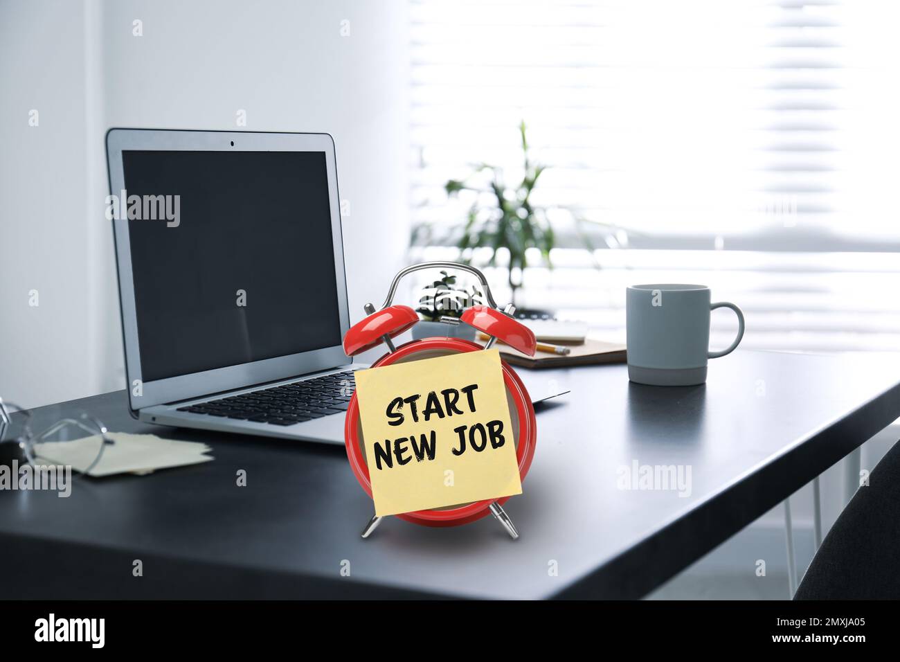 Sticker with text Start New Job on alarm clock near laptop in modern ...