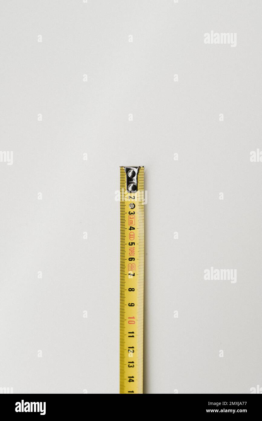 A vertical top view of open yellow measuring tape on white background ...