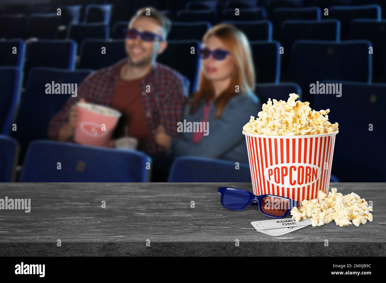 Popcorn, 3D glasses, tickets on table and young couple in cinema hall ...