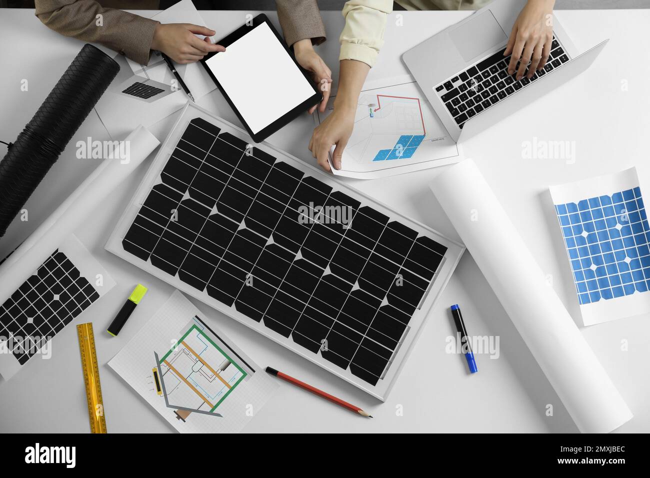 Architects working on house project with solar panels at white table ...