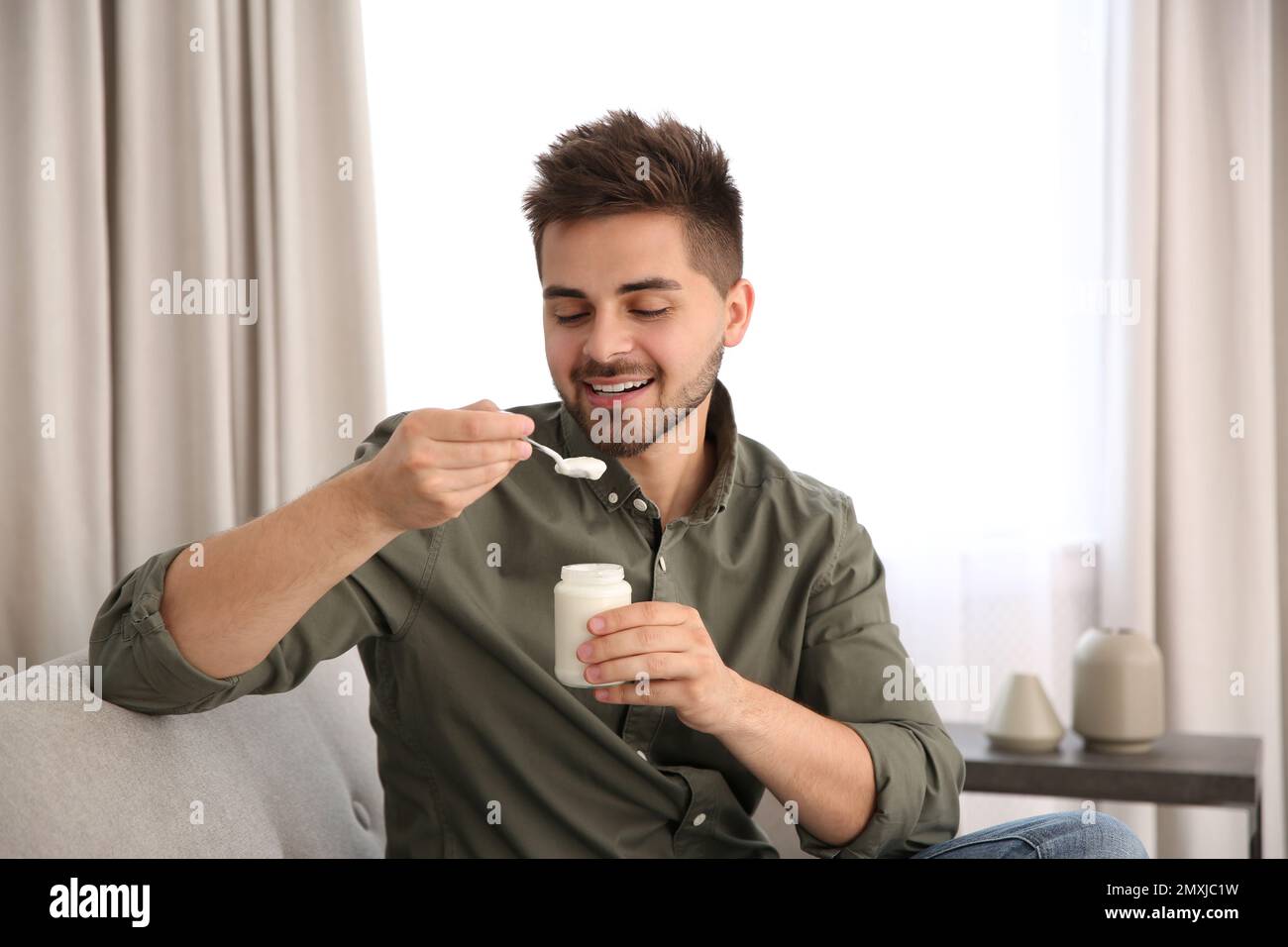 Young man eating yoghurt hi-res stock photography and images - Alamy
